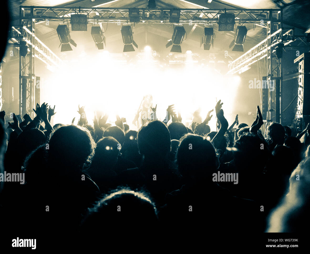 Concert crowd clapping in front of a bright stage Stock Photo - Alamy