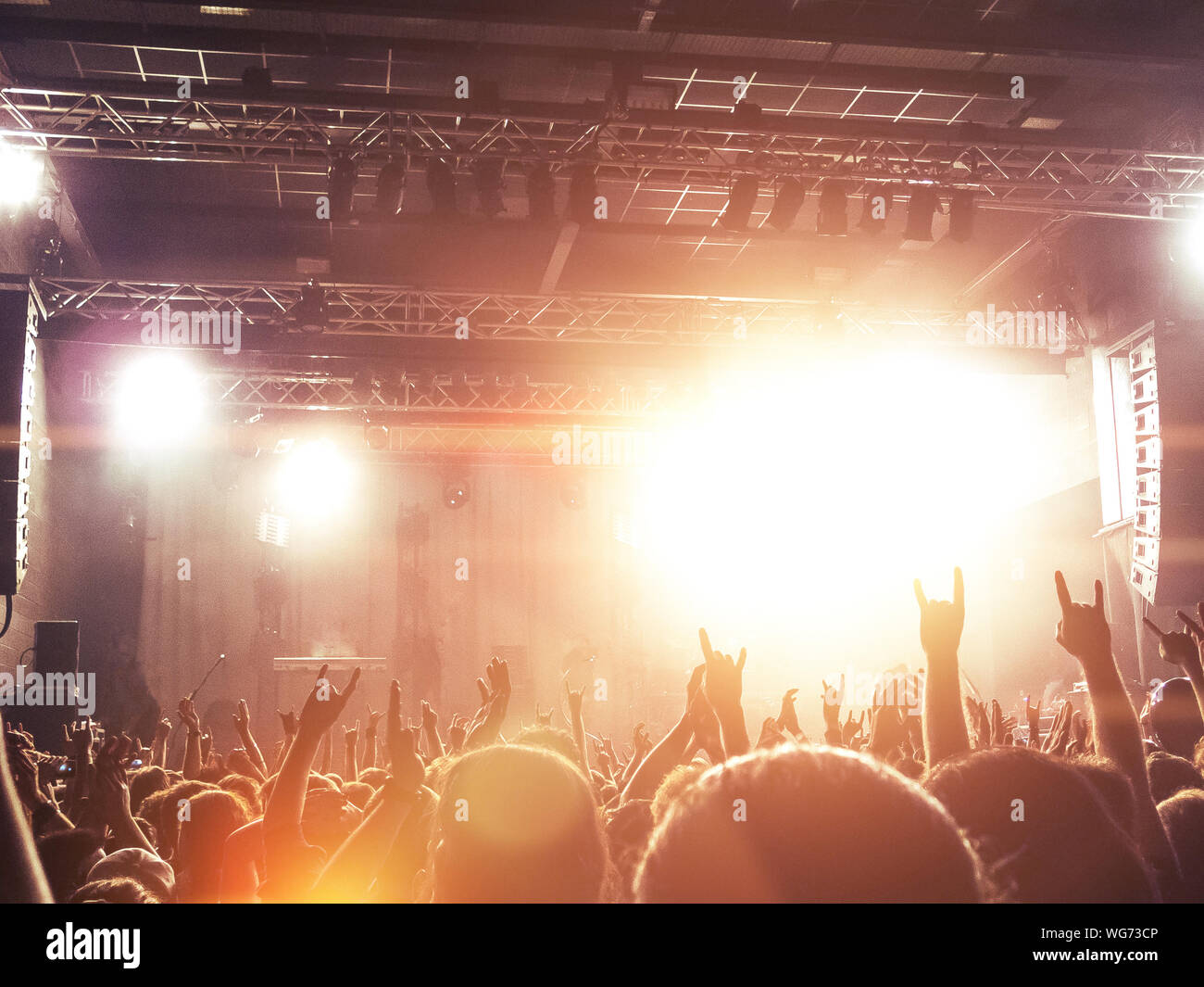 Concert crowd clapping in front of a bright stage Stock Photo - Alamy