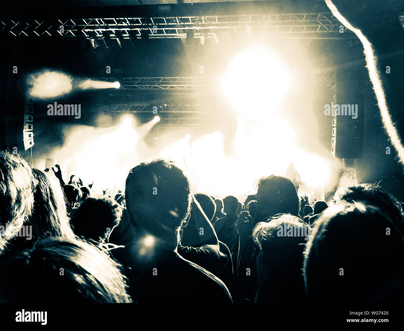 Concert crowd clapping in front of a bright stage Stock Photo - Alamy