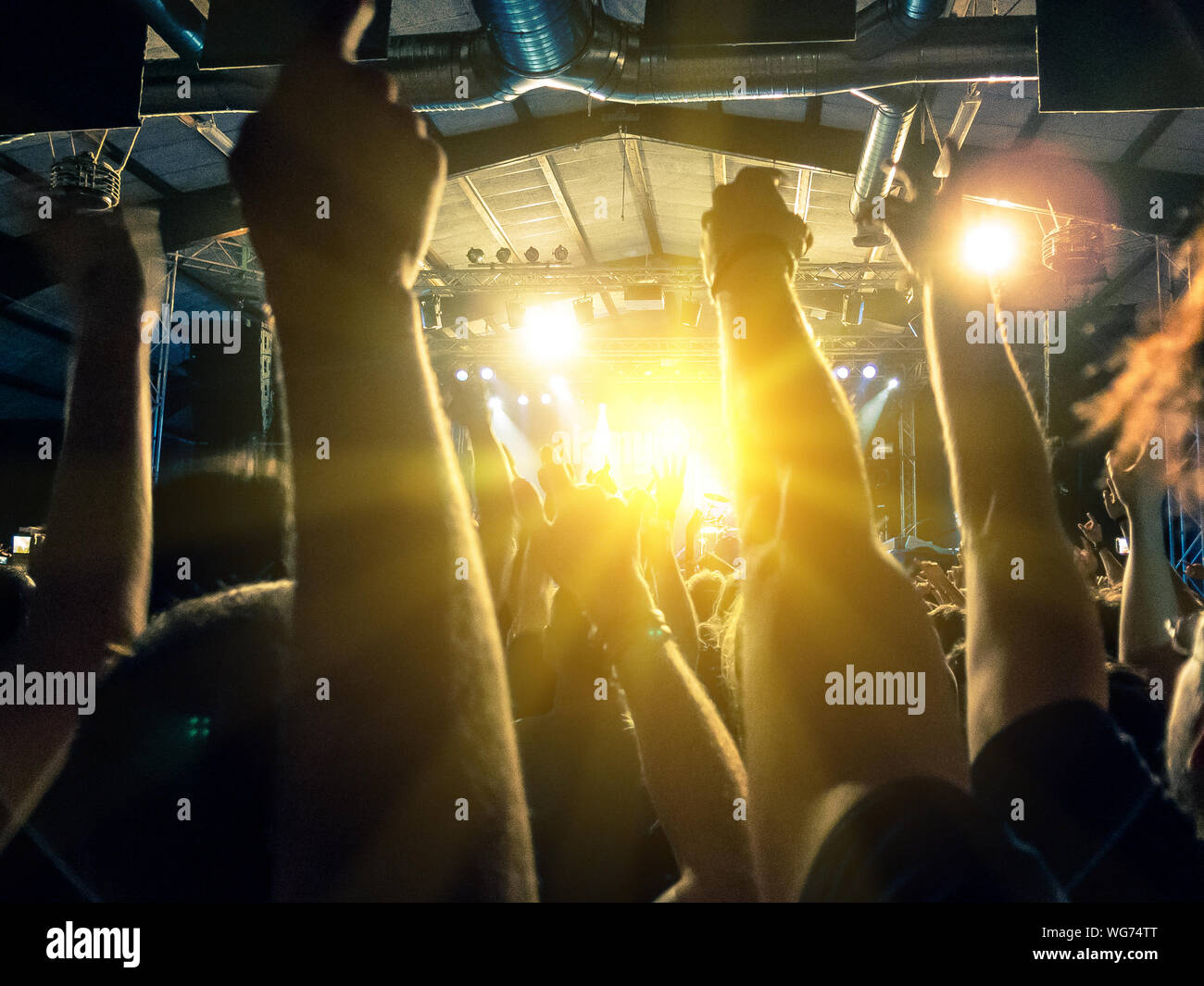 Concert crowd clapping in front of a bright stage Stock Photo - Alamy
