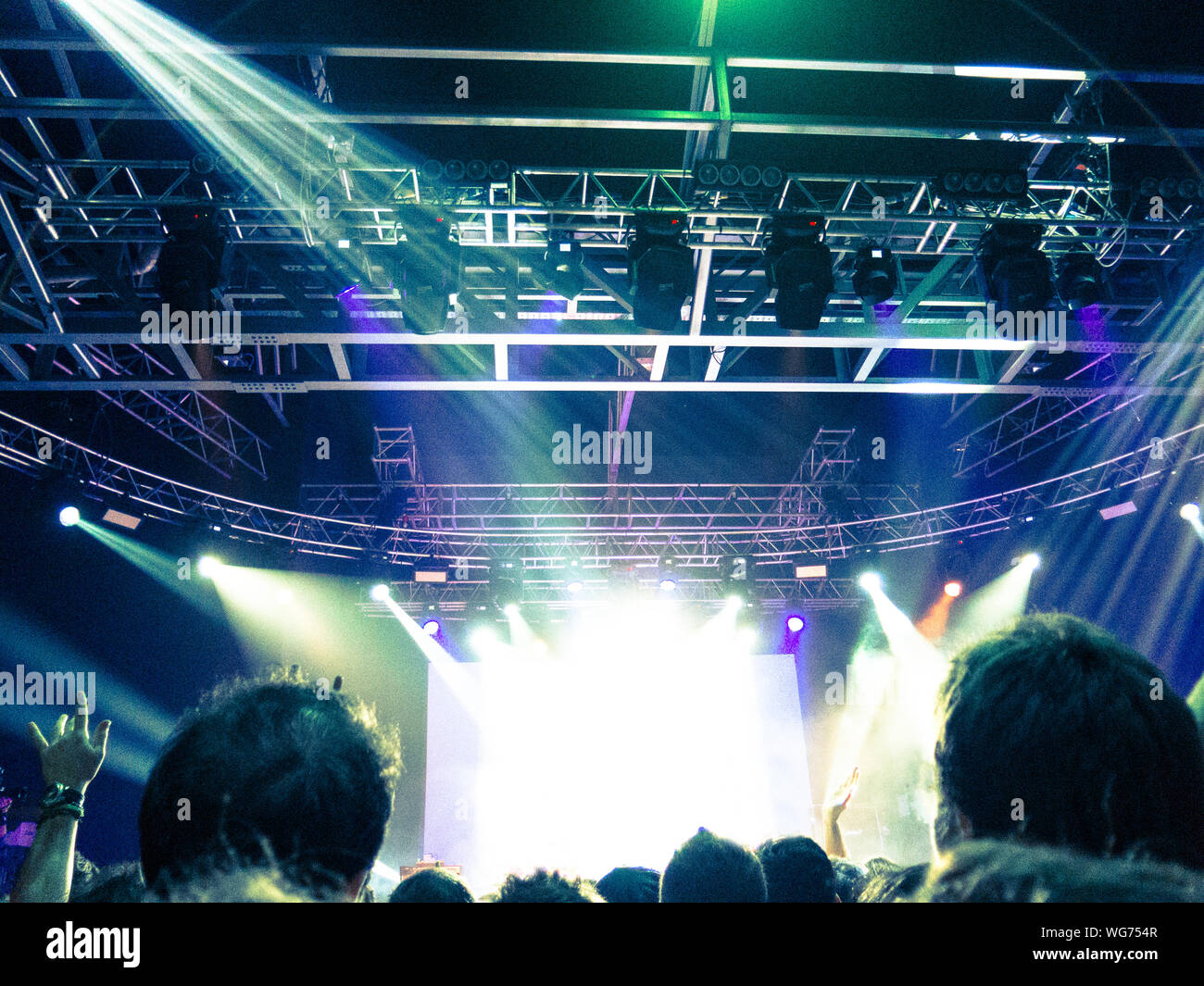 Concert crowd clapping in front of a bright stage Stock Photo - Alamy