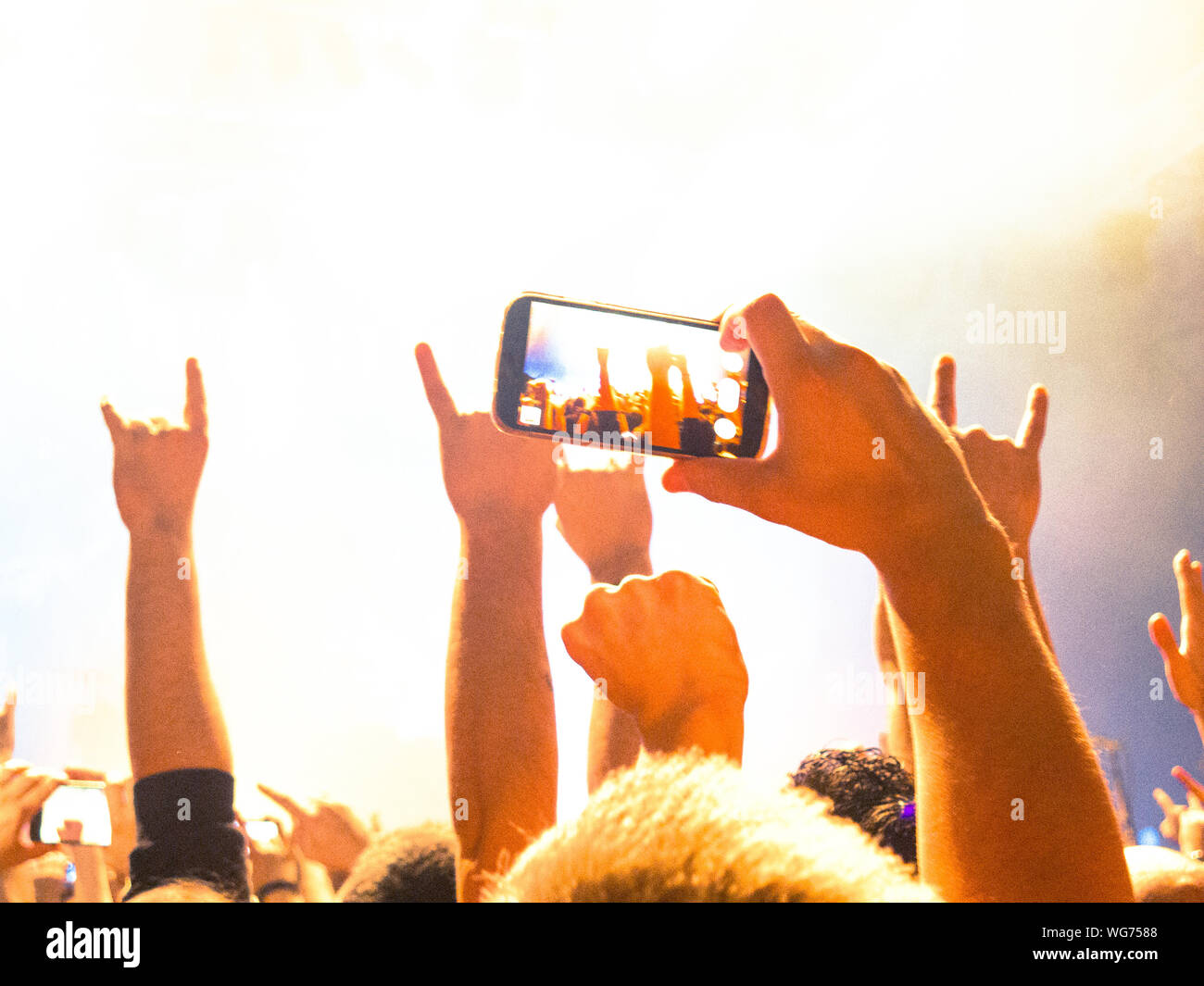Concert crowd clapping in front of a bright stage Stock Photo - Alamy