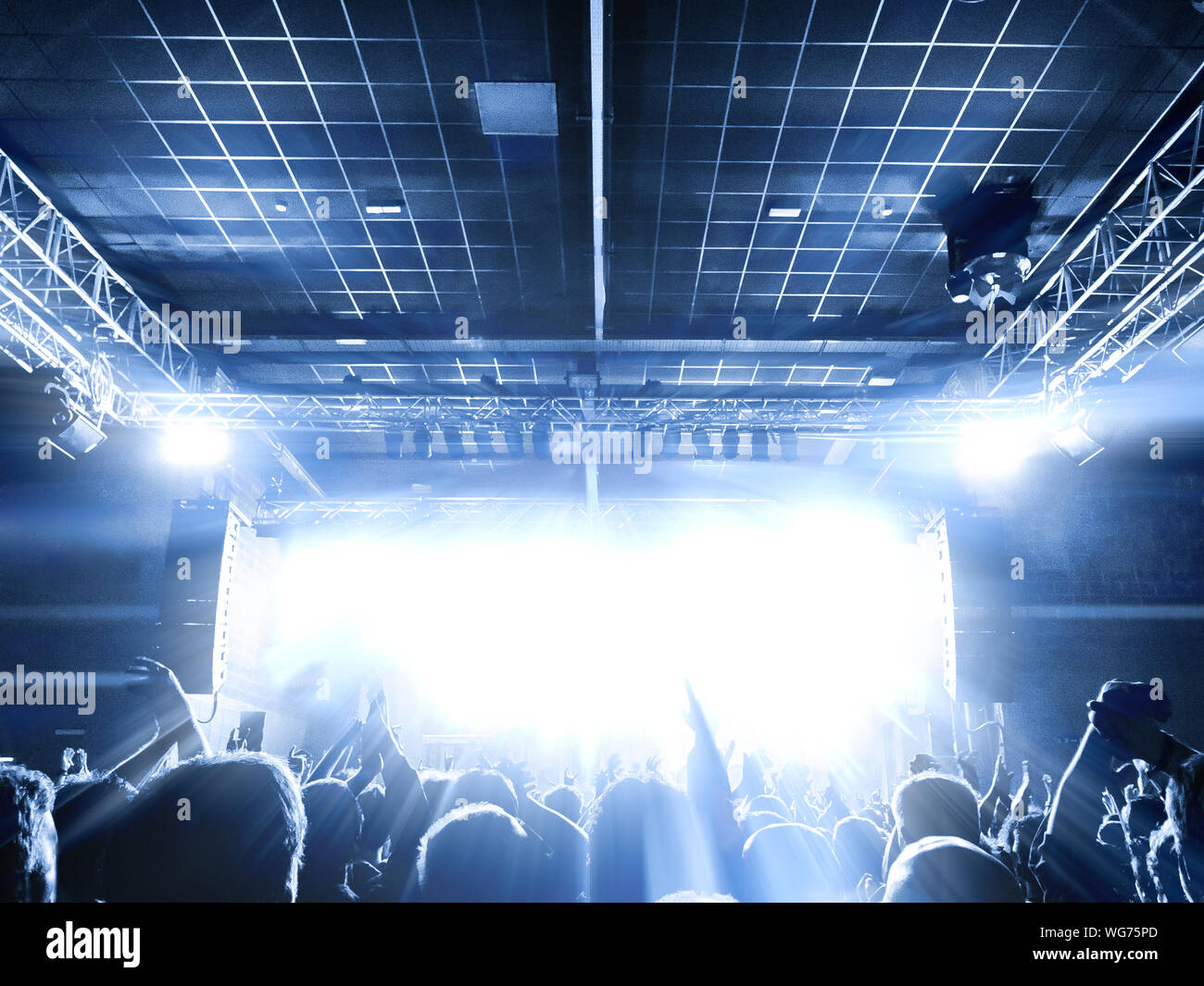 Concert crowd clapping in front of a bright stage Stock Photo - Alamy