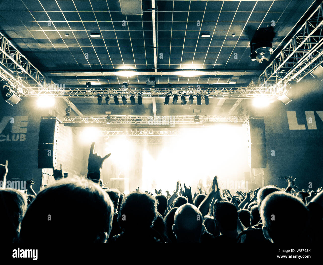 Concert crowd clapping in front of a bright stage Stock Photo - Alamy