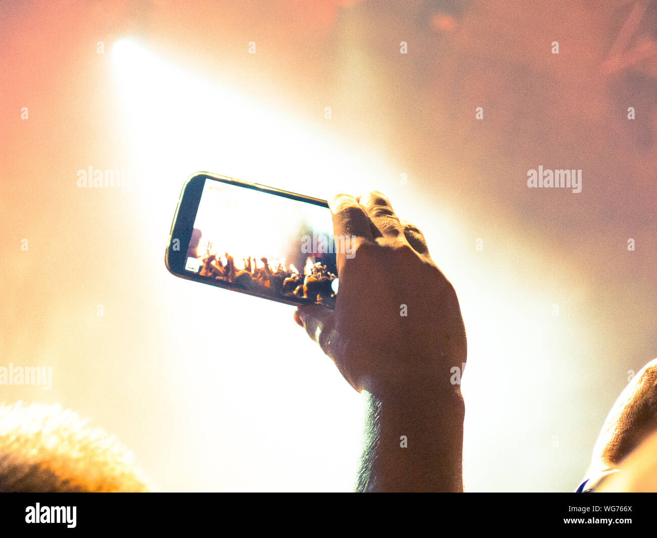 Concert crowd clapping in front of a bright stage Stock Photo - Alamy