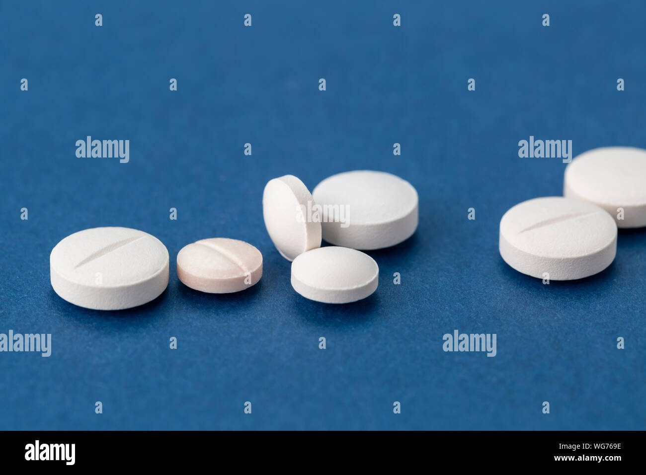 different white drugs on a blue background Stock Photo - Alamy