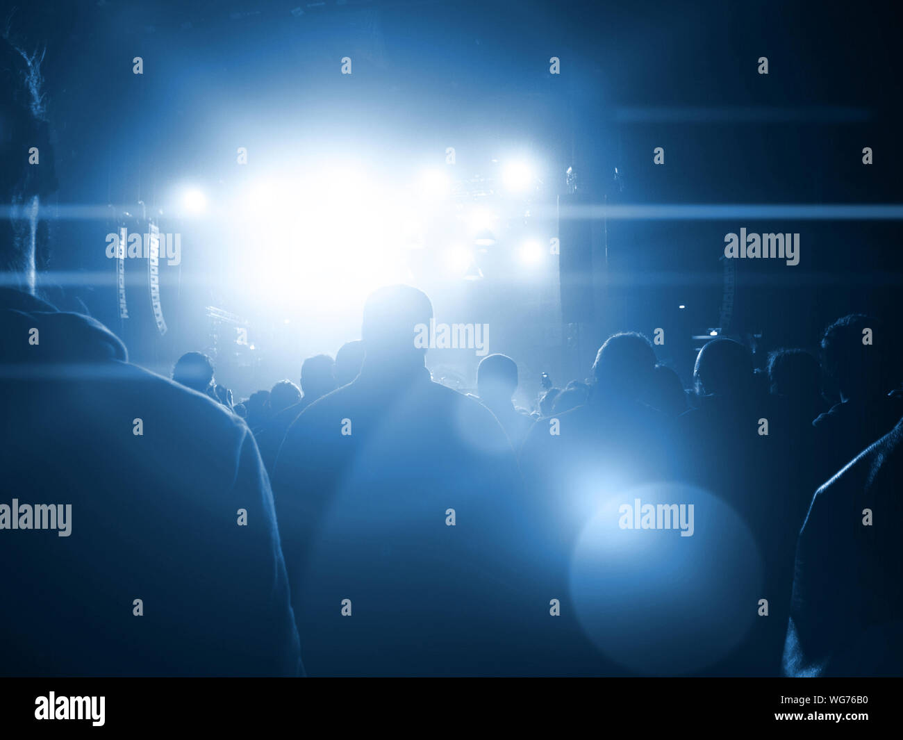 Concert crowd clapping in front of a bright stage Stock Photo - Alamy