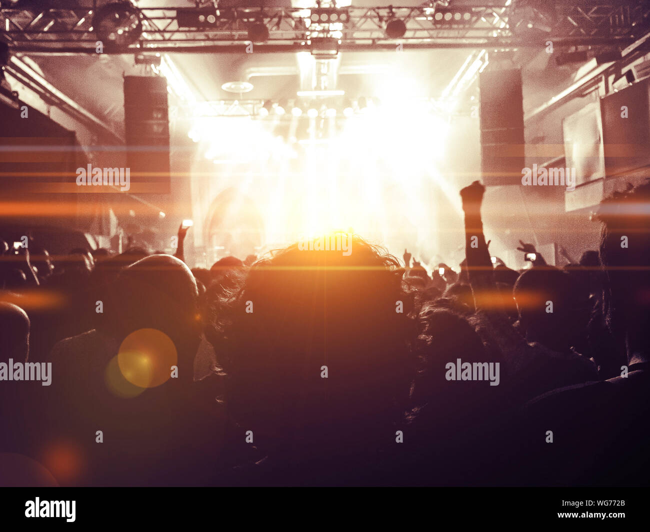 Concert crowd clapping in front of a bright stage Stock Photo - Alamy