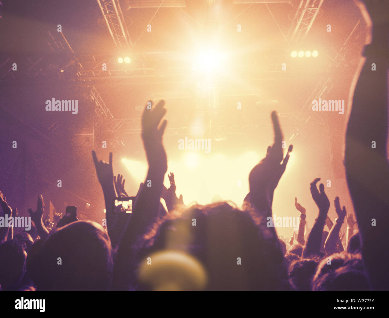Concert crowd clapping in front of a bright stage Stock Photo - Alamy