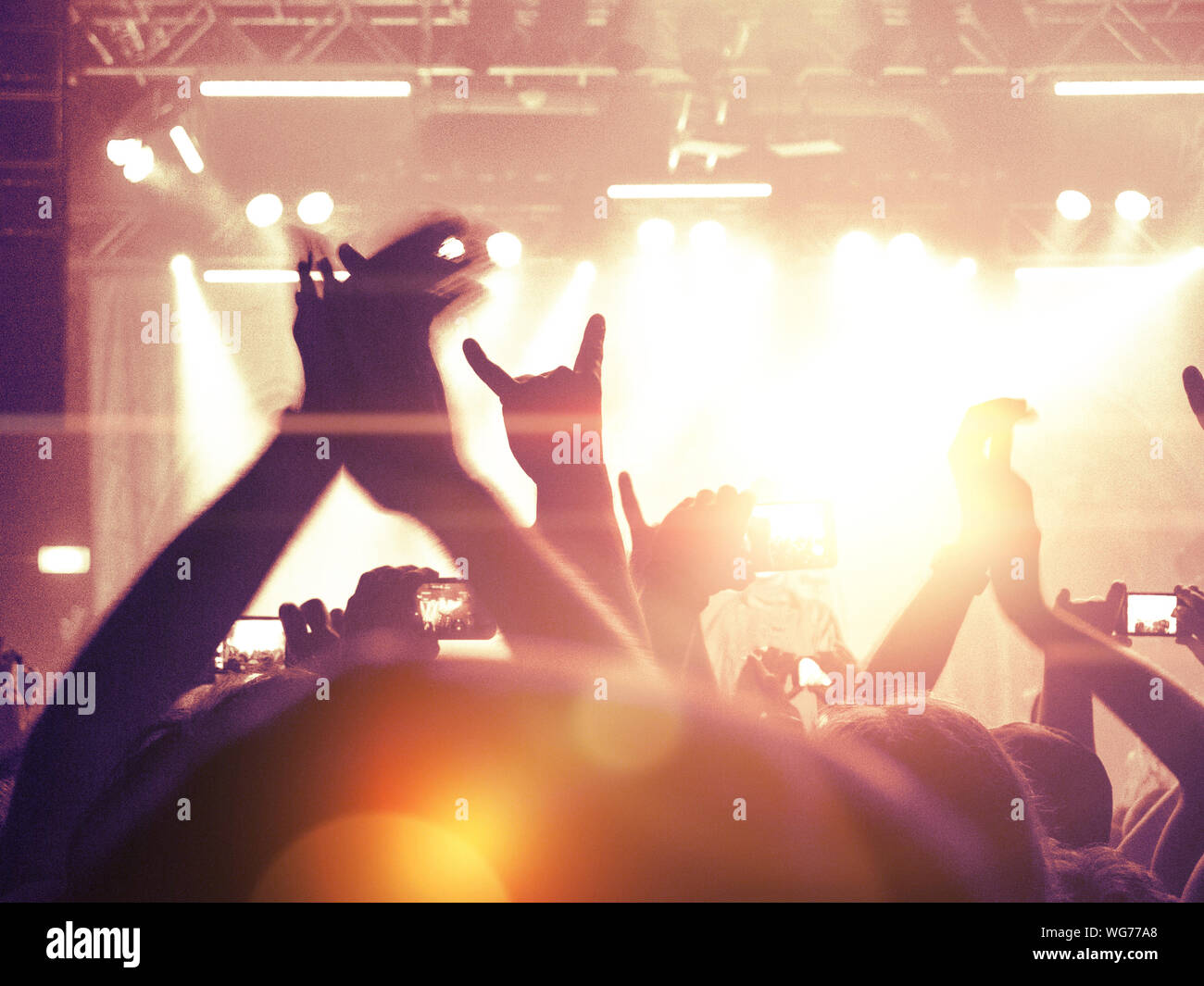 Concert crowd clapping in front of a bright stage Stock Photo - Alamy