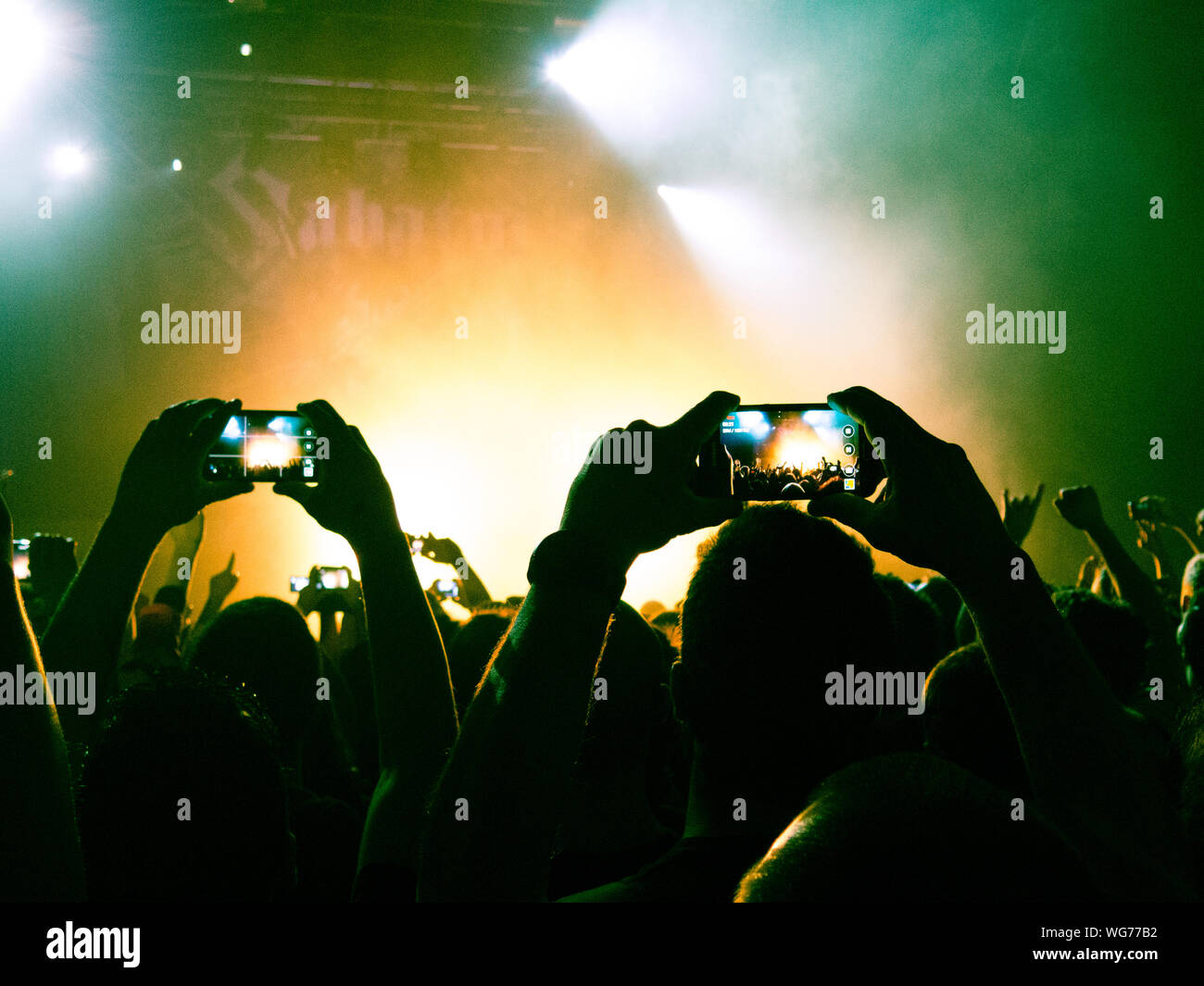 Concert crowd clapping in front of a bright stage Stock Photo - Alamy