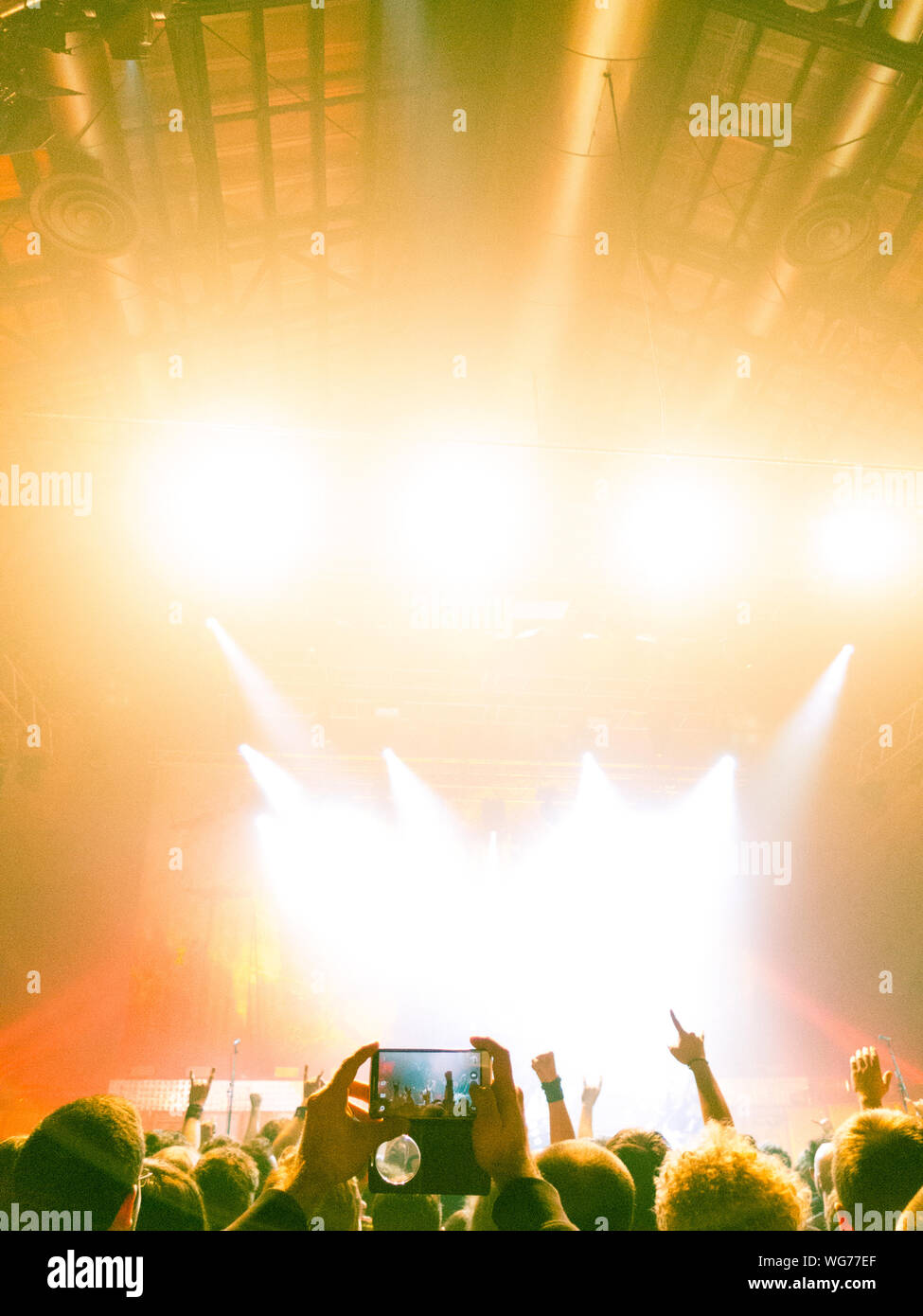 Concert crowd clapping in front of a bright stage Stock Photo - Alamy