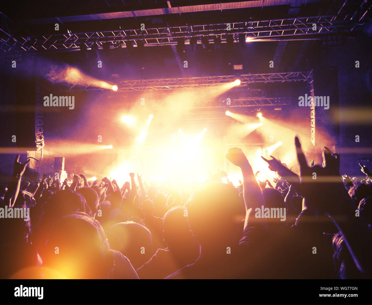 Concert crowd clapping in front of a bright stage Stock Photo - Alamy