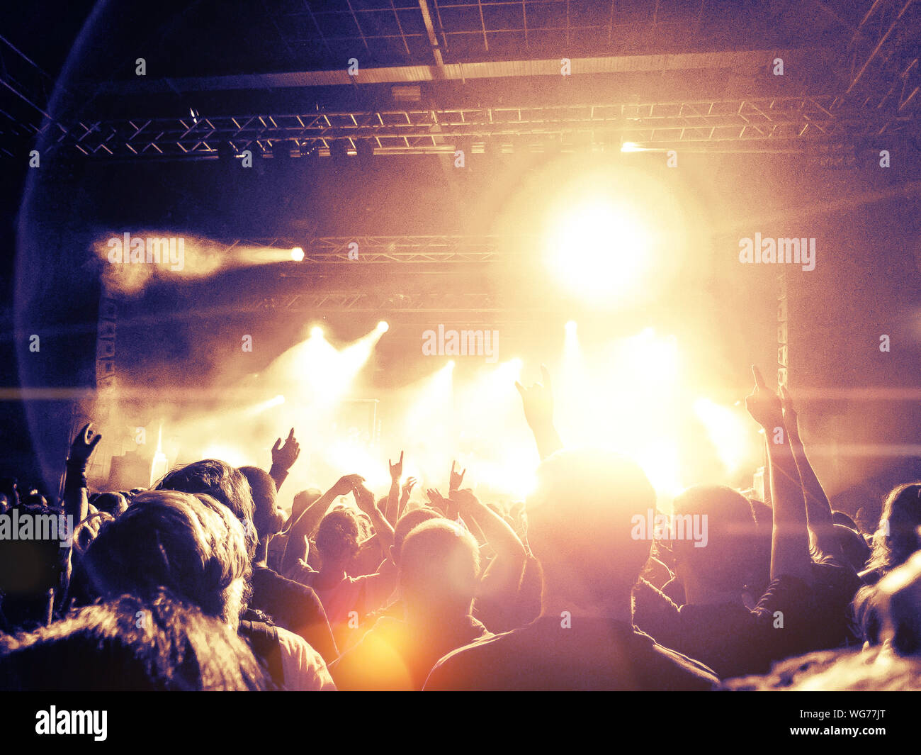 Concert crowd clapping in front of a bright stage Stock Photo - Alamy