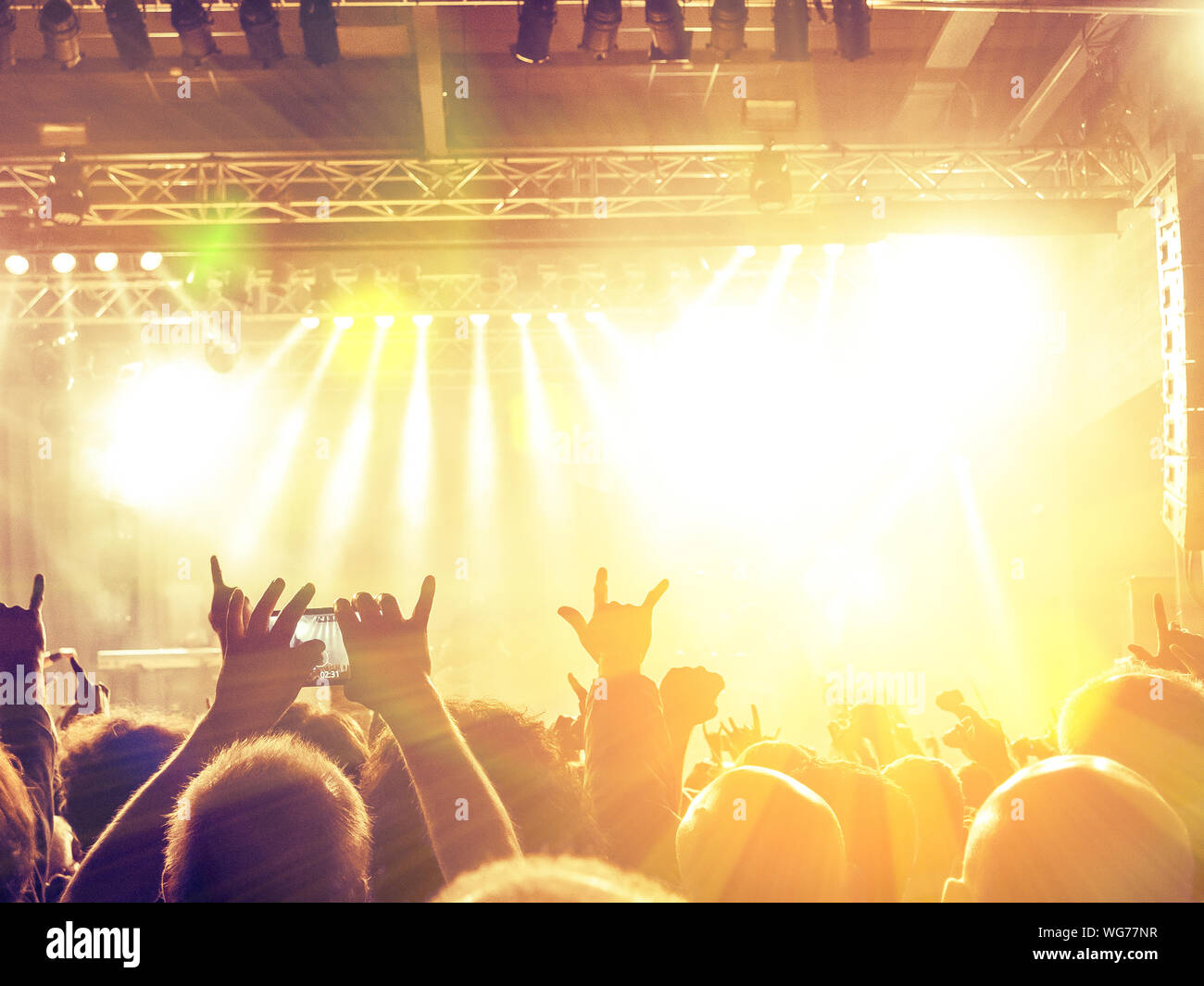 Concert crowd clapping in front of a bright stage Stock Photo - Alamy