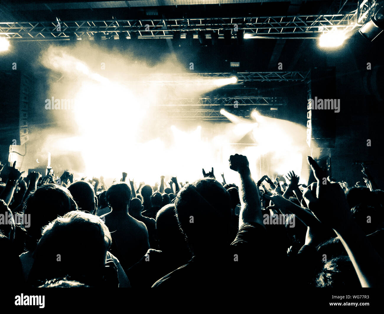 Concert crowd clapping in front of a bright stage Stock Photo - Alamy
