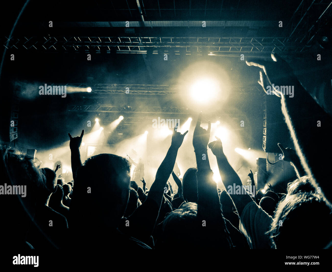 Concert crowd clapping in front of a bright stage Stock Photo - Alamy