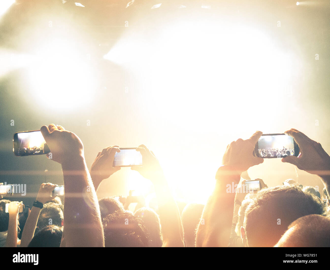 Concert crowd clapping in front of a bright stage Stock Photo - Alamy