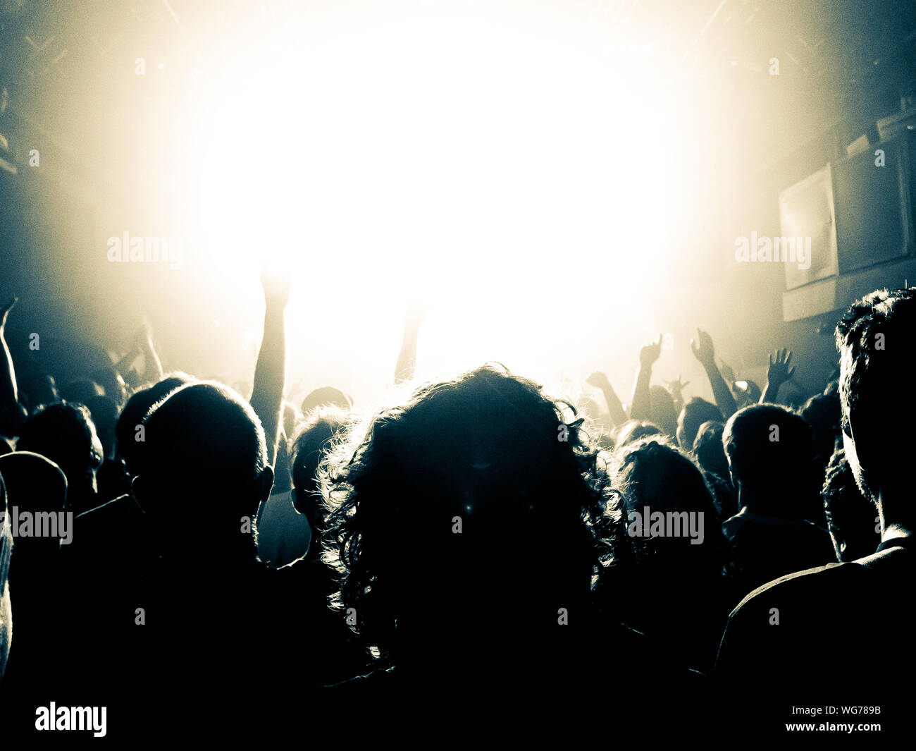 Concert crowd clapping in front of a bright stage Stock Photo - Alamy