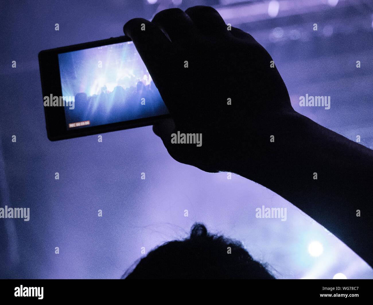 Concert crowd clapping in front of a bright stage Stock Photo - Alamy