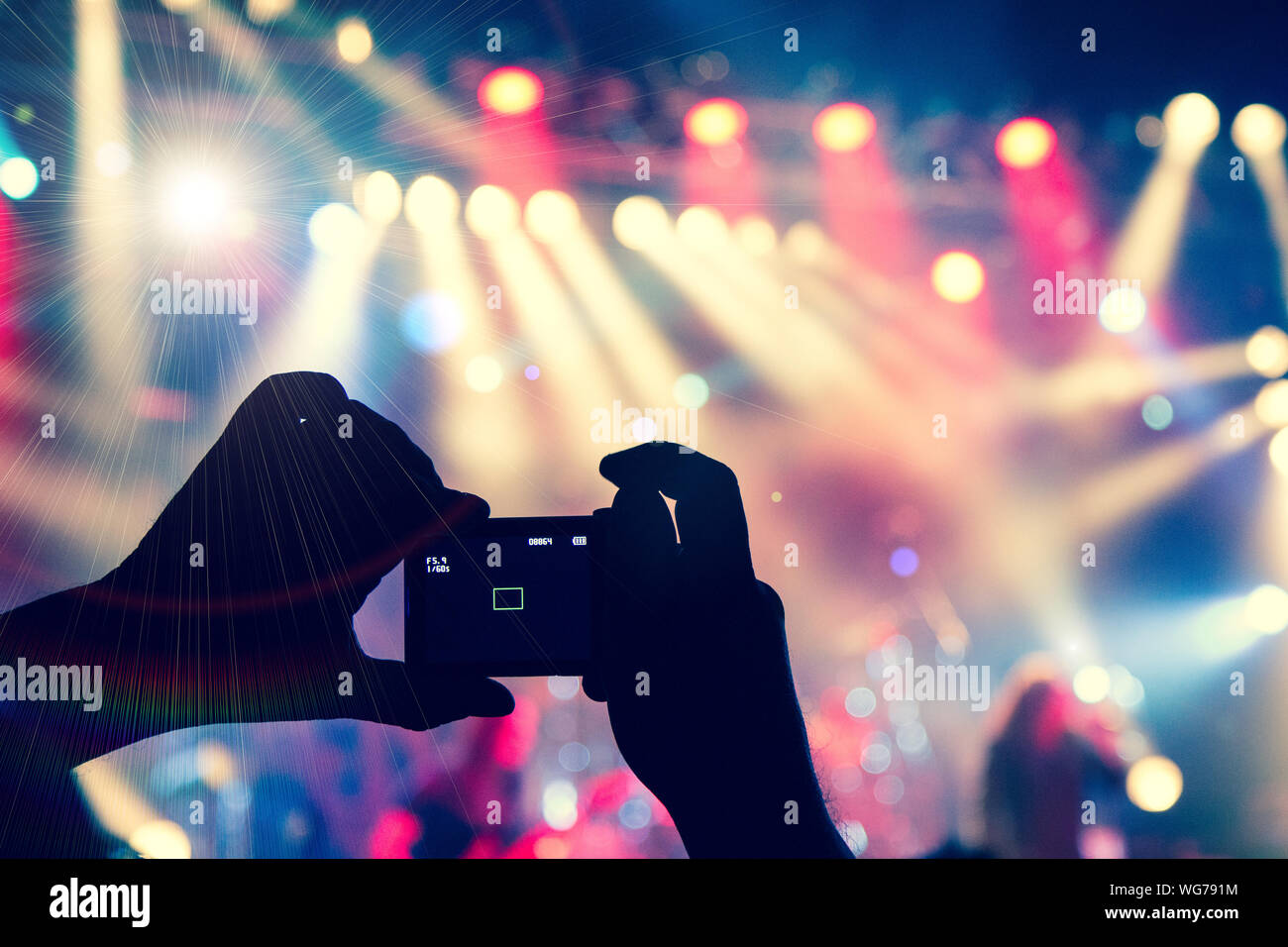 Concert crowd clapping in front of a bright stage Stock Photo - Alamy