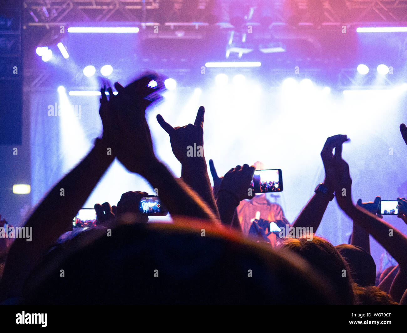 Concert crowd clapping in front of a bright stage Stock Photo - Alamy