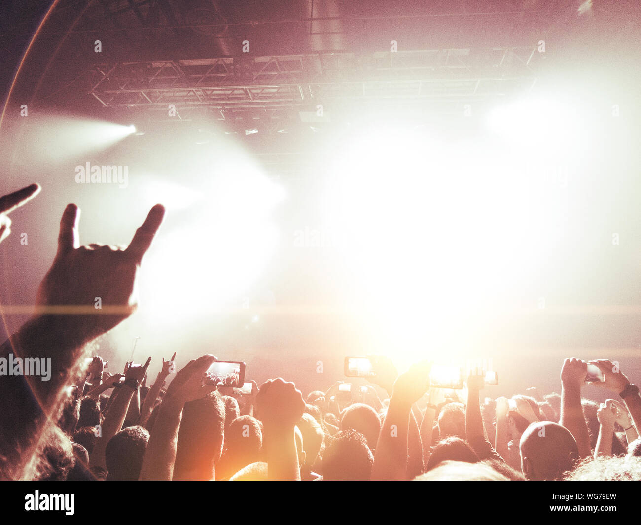 Concert crowd clapping in front of a bright stage Stock Photo - Alamy