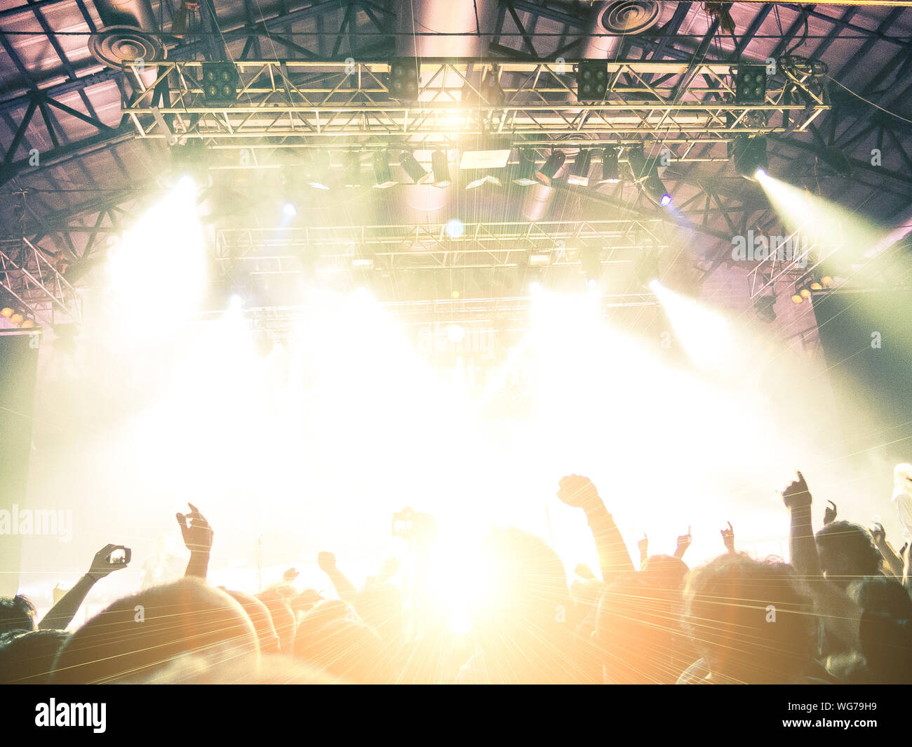 Concert crowd clapping in front of a bright stage Stock Photo - Alamy