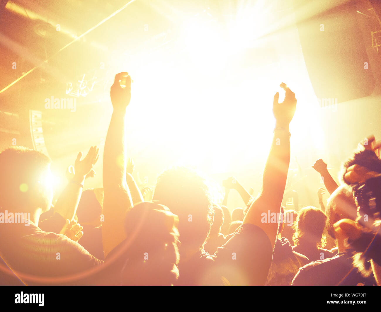 Concert crowd clapping in front of a bright stage Stock Photo - Alamy