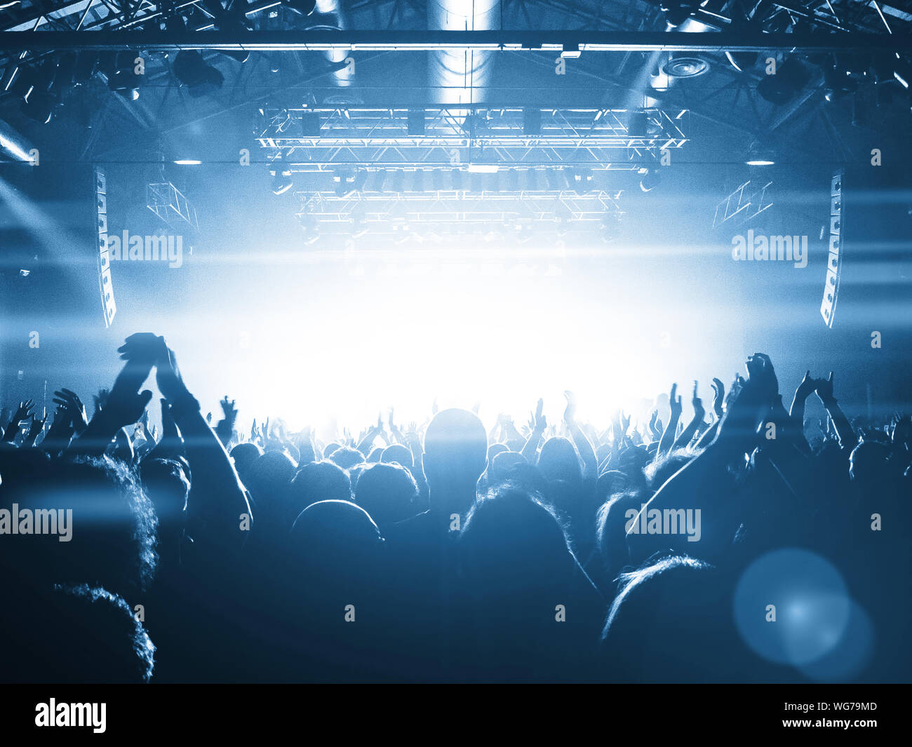 Concert crowd clapping in front of a bright stage Stock Photo - Alamy
