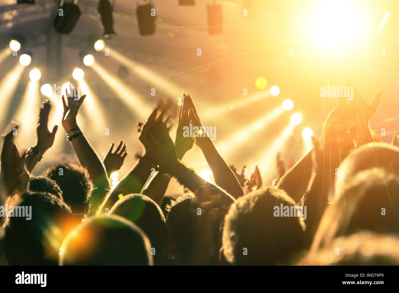 Concert crowd clapping in front of a bright stage Stock Photo - Alamy