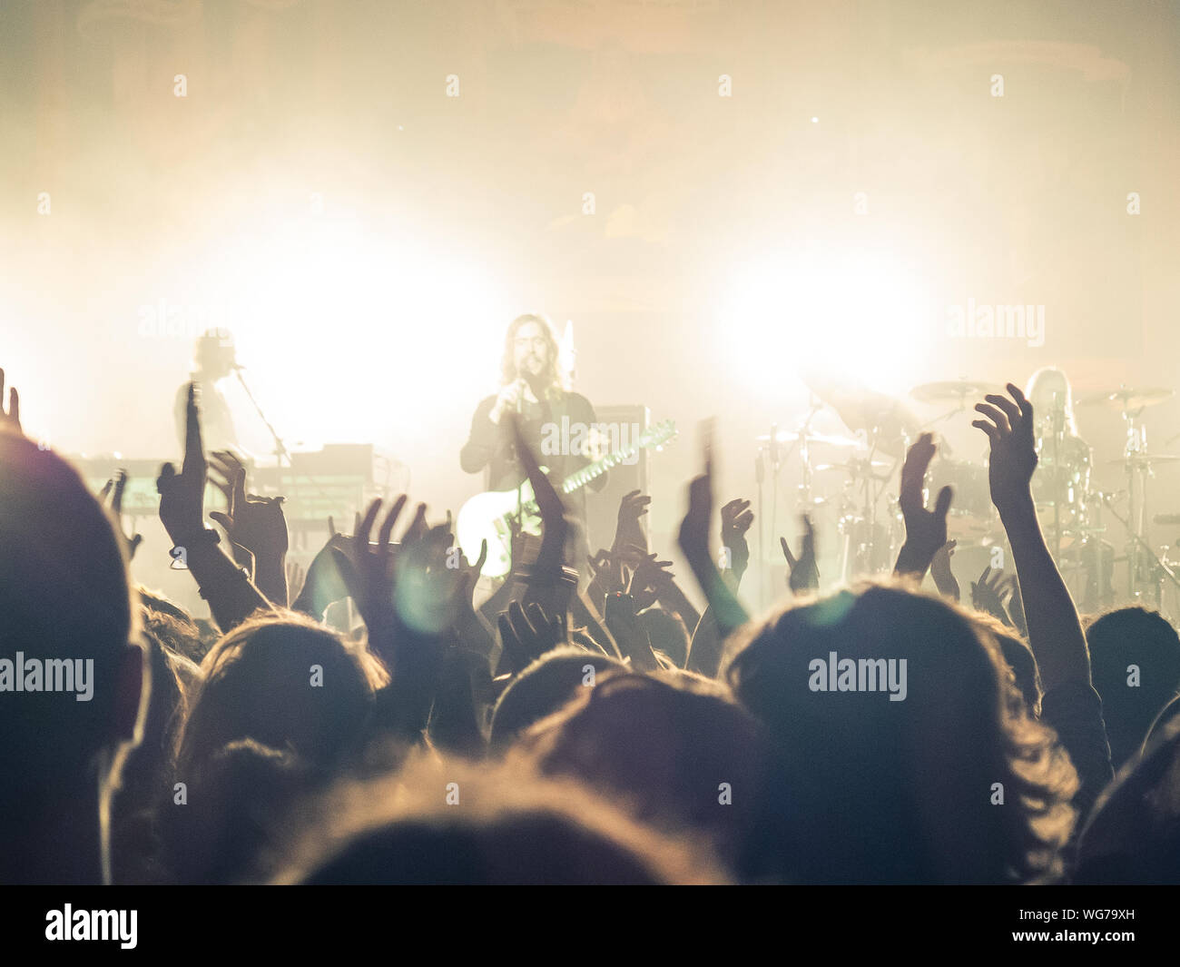 Concert crowd clapping in front of a bright stage Stock Photo - Alamy