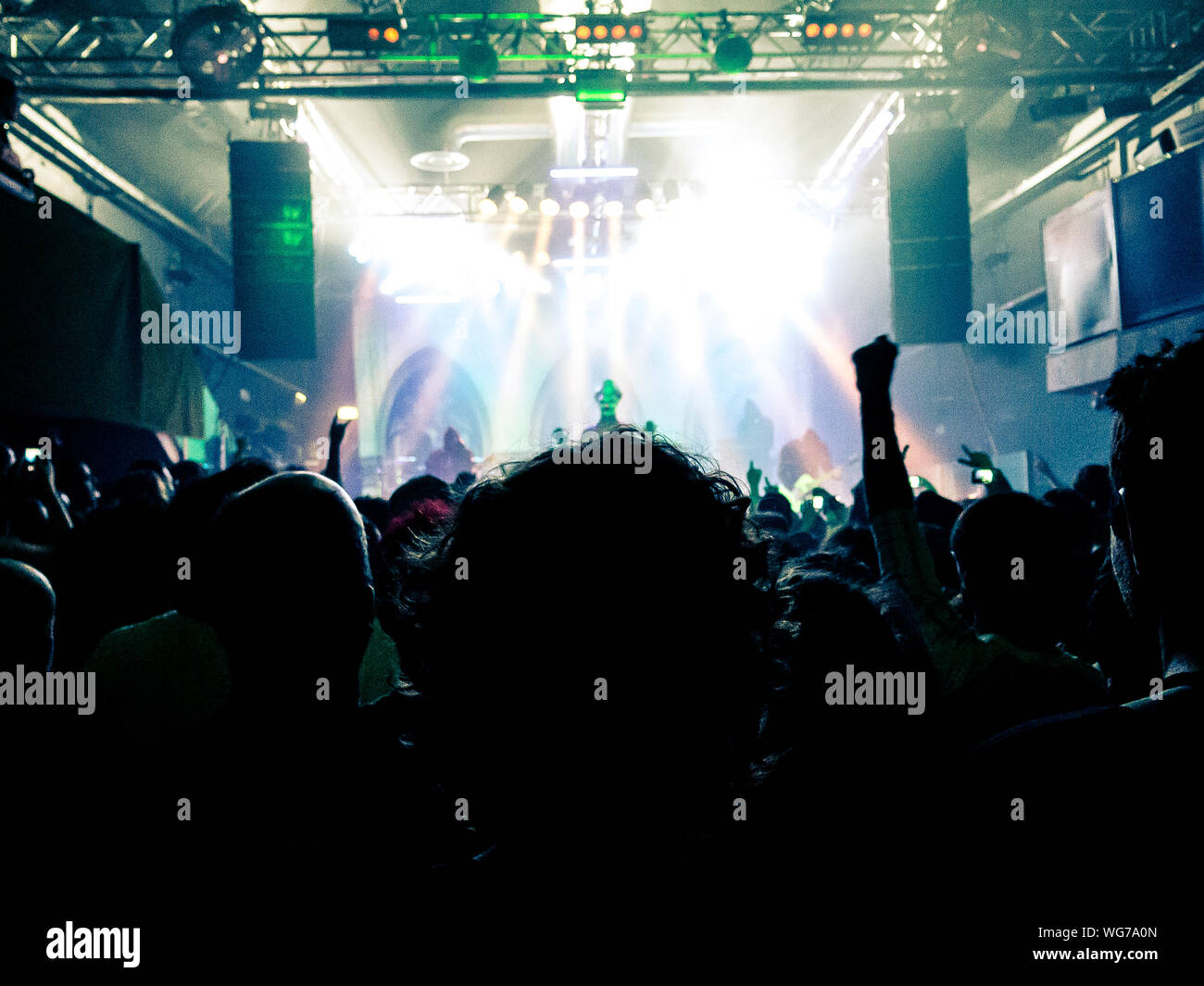 Concert crowd clapping in front of a bright stage Stock Photo - Alamy