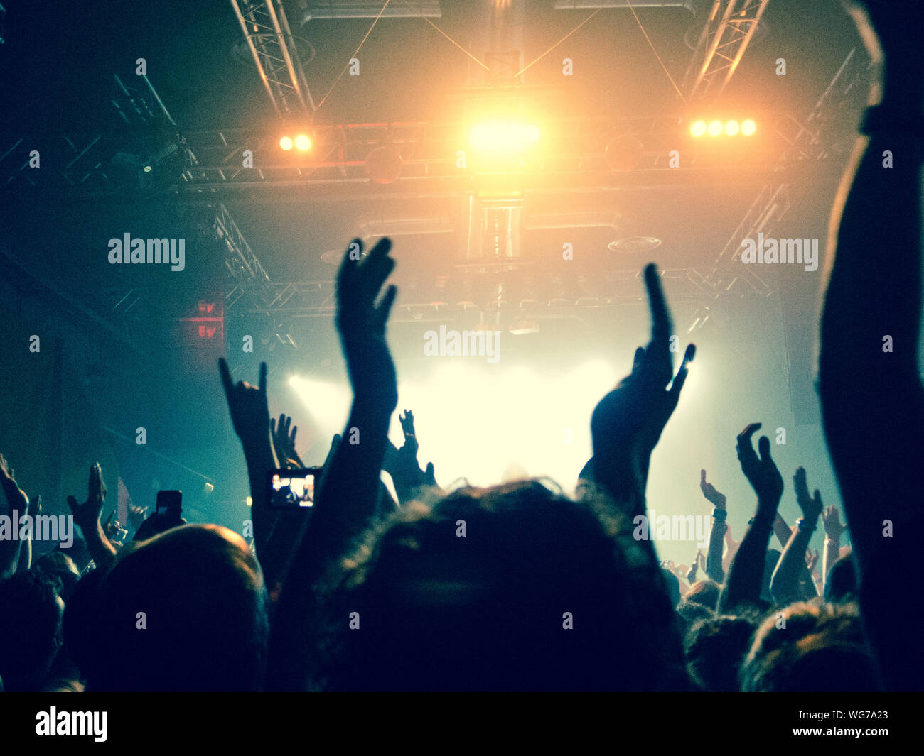 Concert crowd clapping in front of a bright stage Stock Photo - Alamy