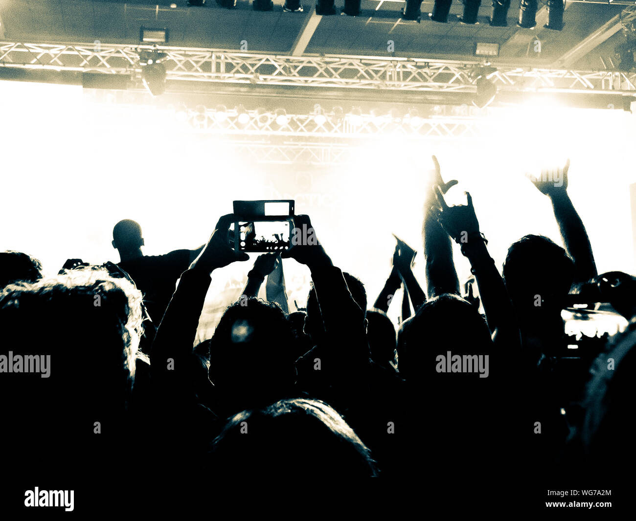 Concert crowd clapping in front of a bright stage Stock Photo - Alamy