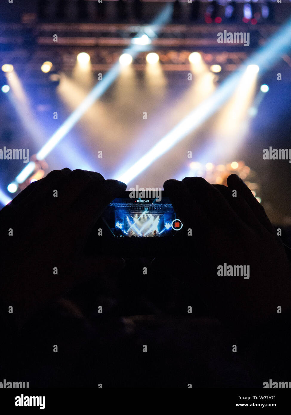 Concert crowd clapping in front of a bright stage Stock Photo - Alamy