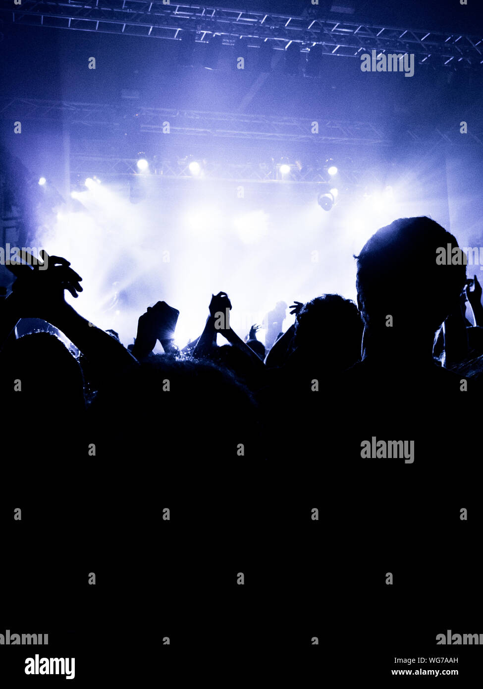 Concert crowd clapping in front of a bright stage Stock Photo - Alamy