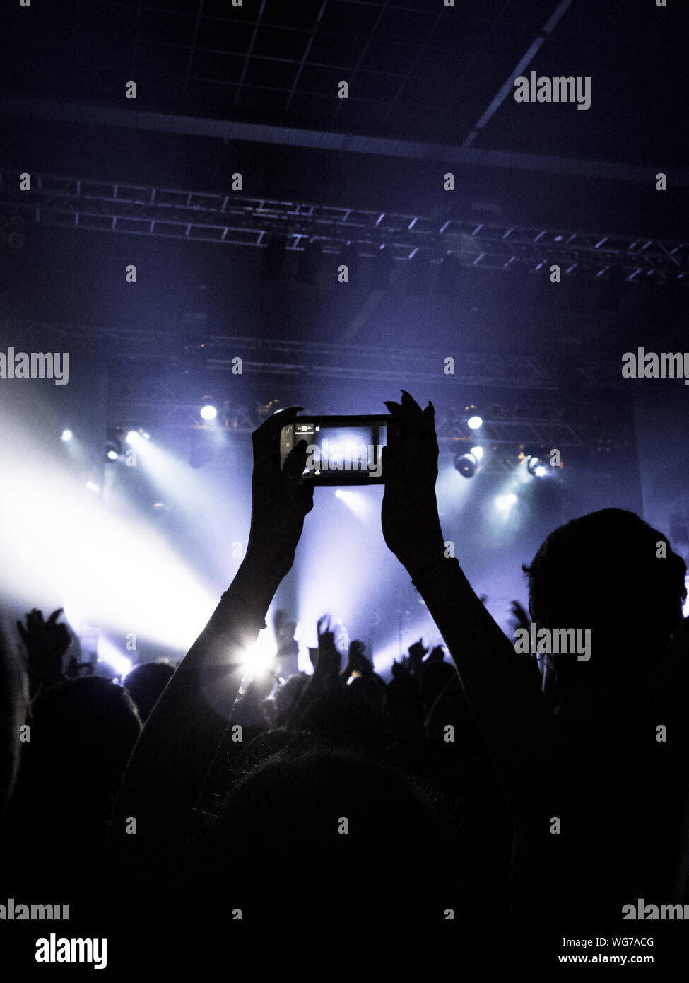 Concert crowd clapping in front of a bright stage Stock Photo - Alamy