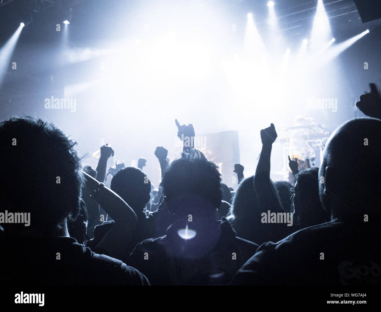 Concert crowd clapping in front of a bright stage Stock Photo - Alamy