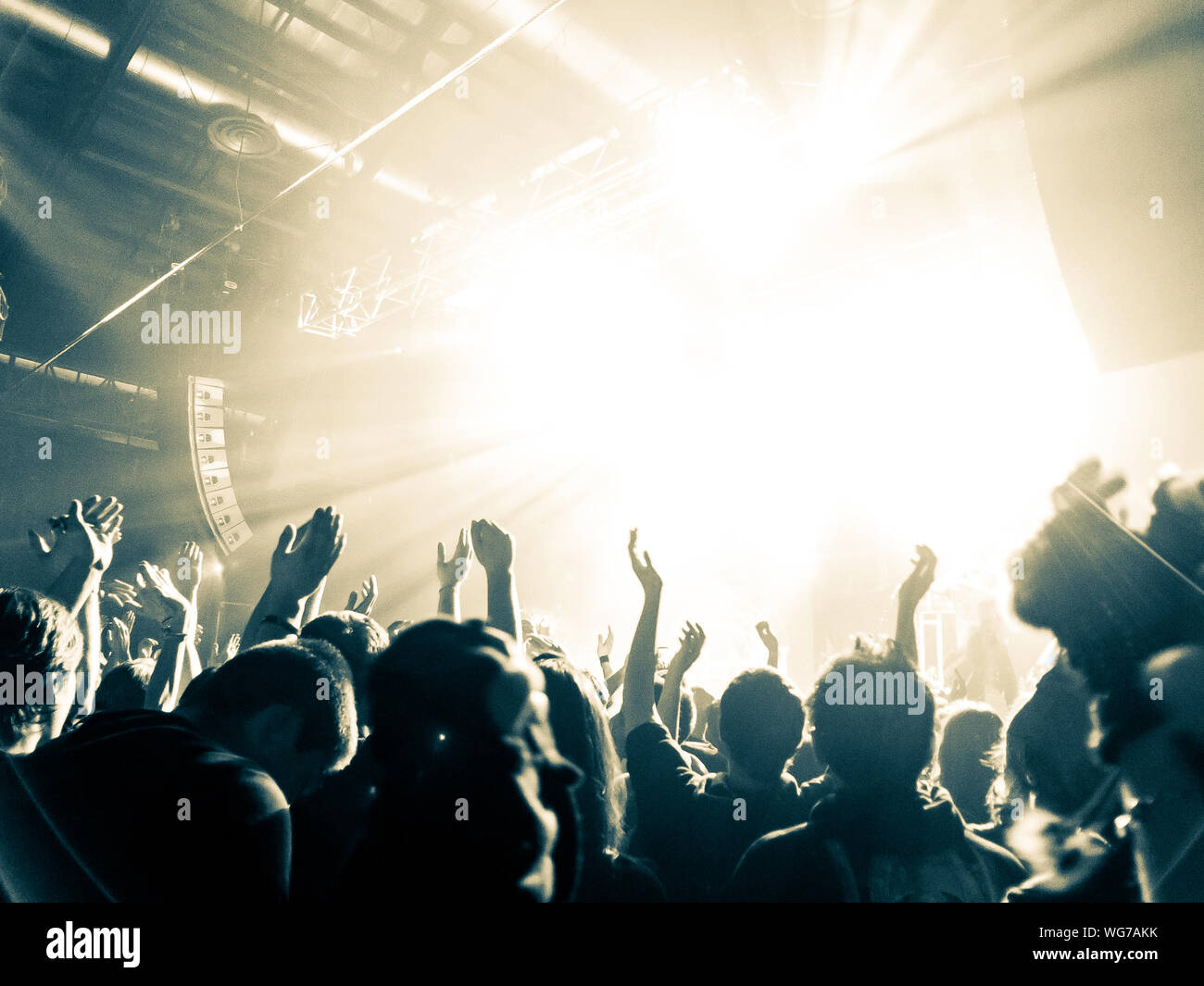 Concert crowd clapping in front of a bright stage Stock Photo - Alamy