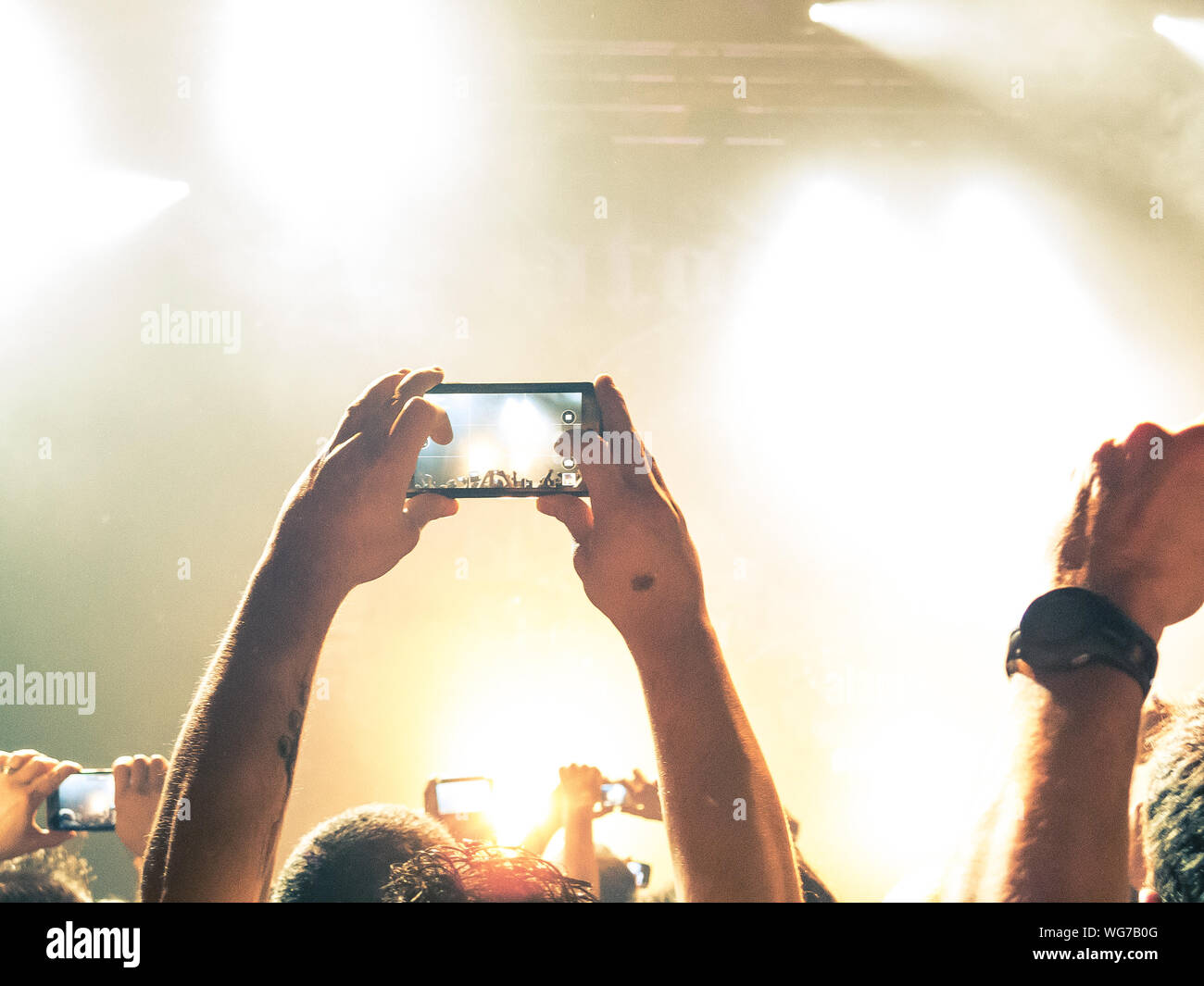 Concert crowd clapping in front of a bright stage Stock Photo - Alamy