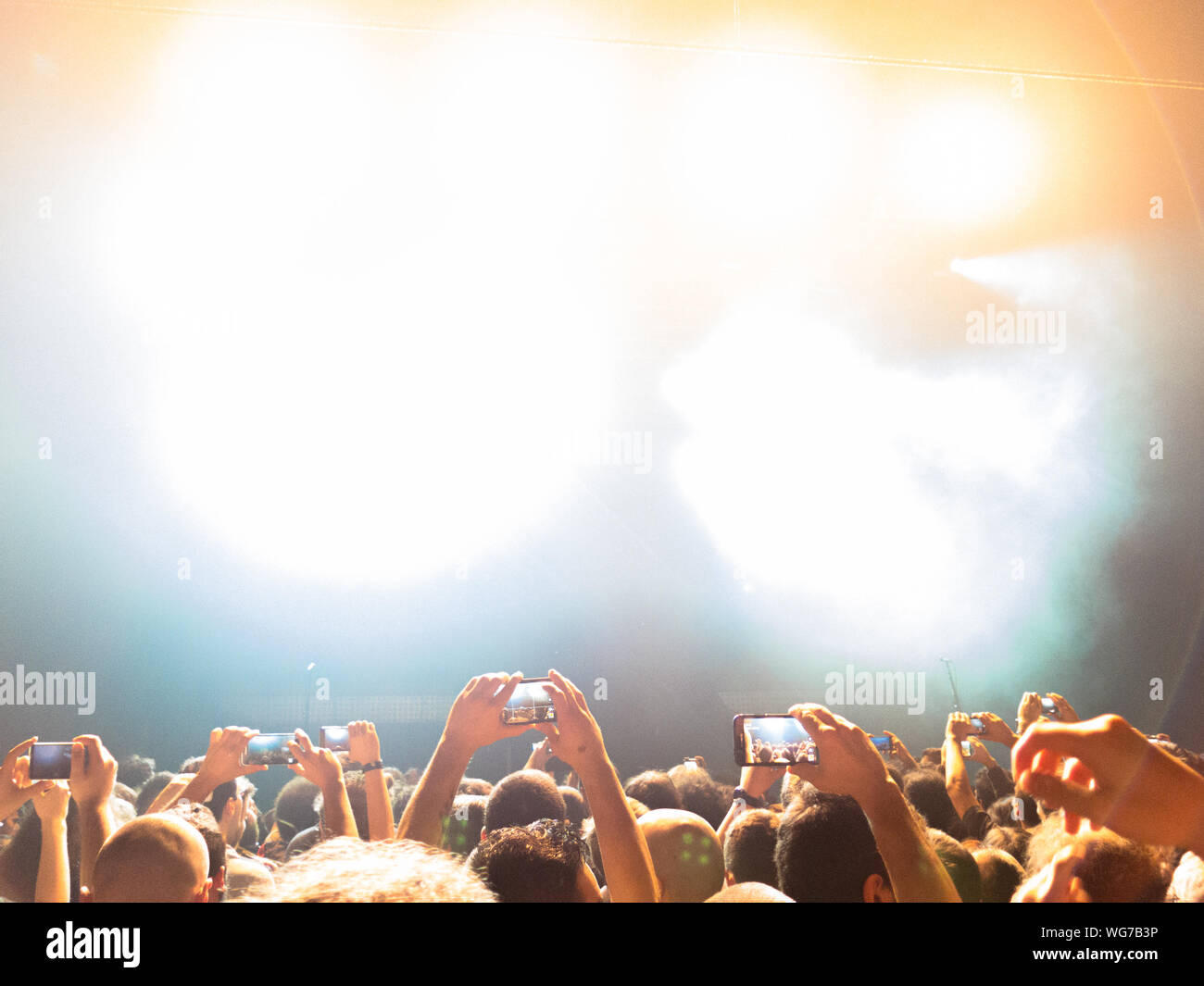 Concert crowd clapping in front of a bright stage Stock Photo - Alamy