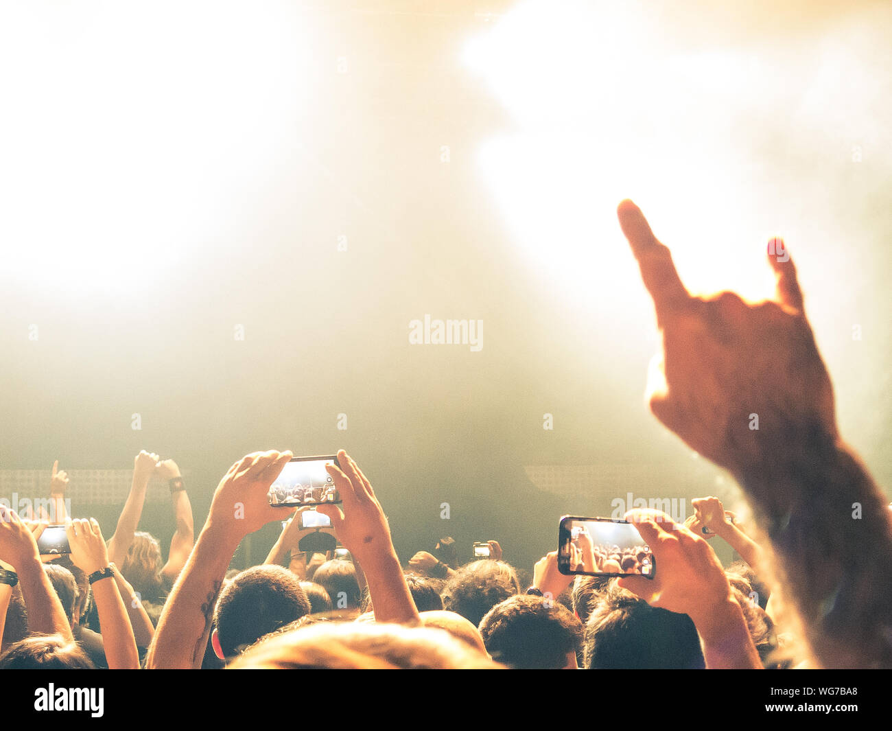 Concert crowd clapping in front of a bright stage Stock Photo - Alamy