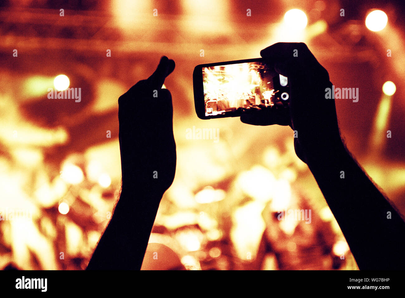 Concert crowd clapping in front of a bright stage Stock Photo - Alamy