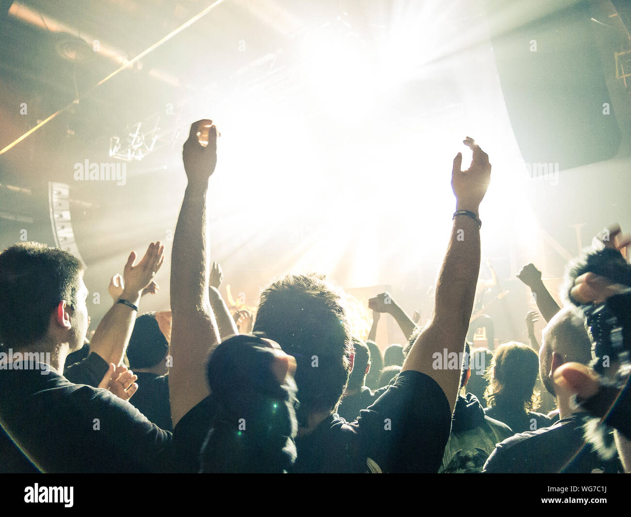 Concert crowd clapping in front of a bright stage Stock Photo - Alamy