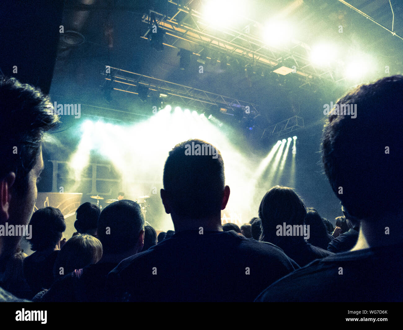 Concert crowd clapping in front of a bright stage Stock Photo - Alamy
