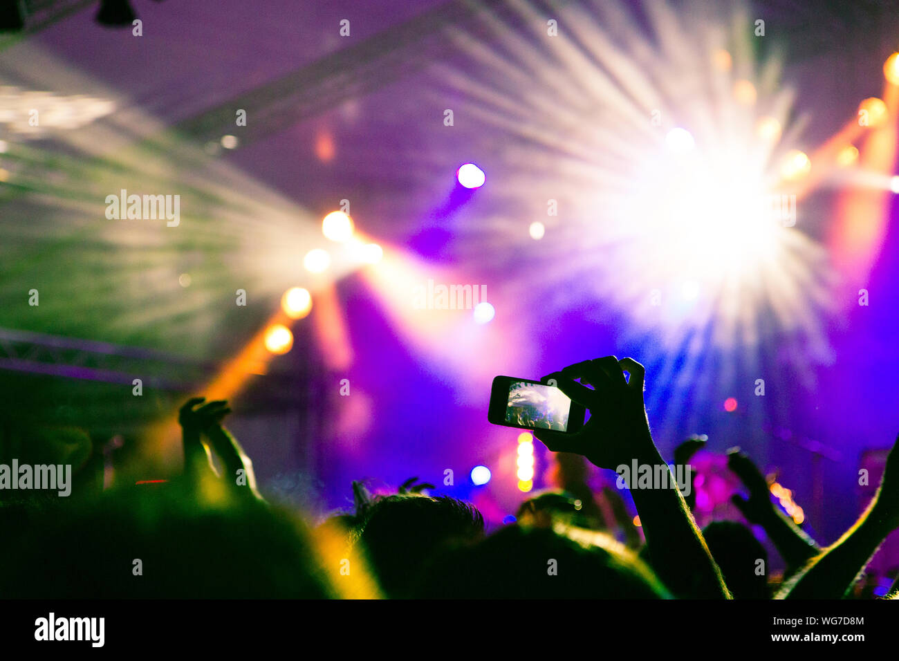 Concert crowd clapping in front of a bright stage Stock Photo - Alamy