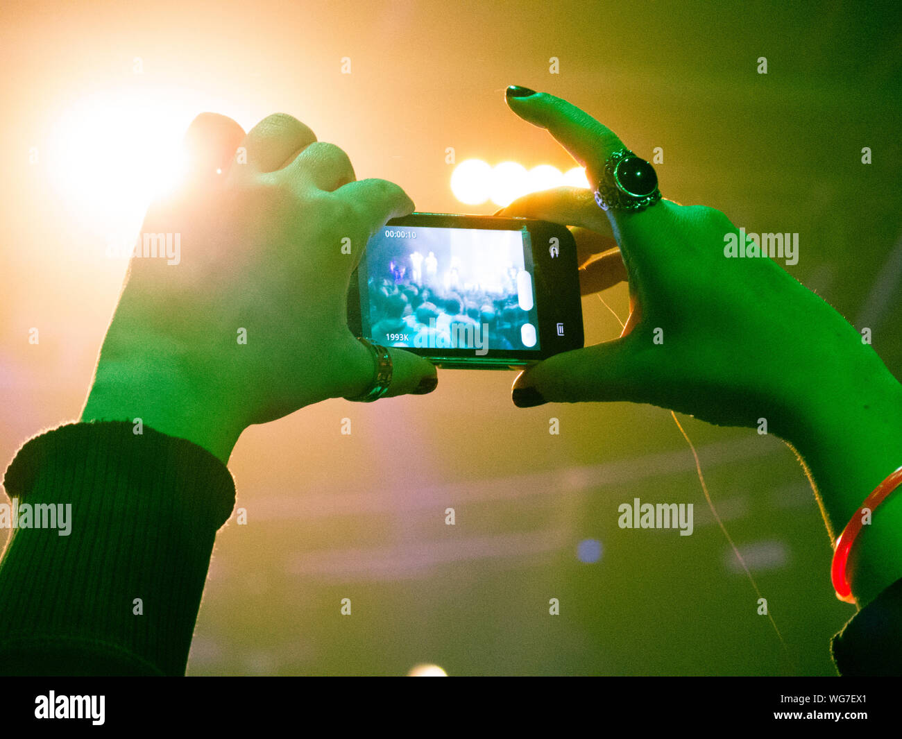 Concert crowd clapping in front of a bright stage Stock Photo - Alamy