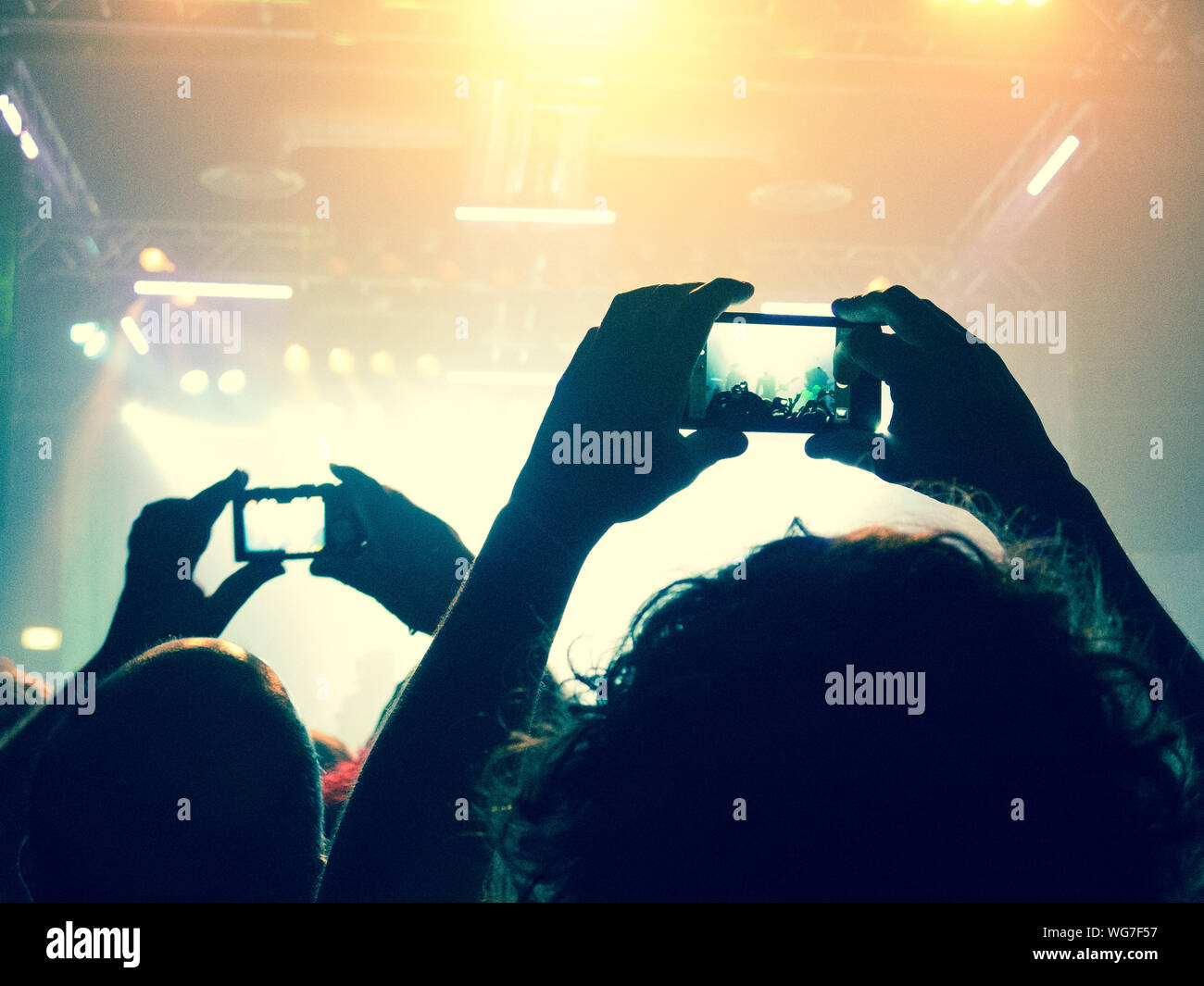 Concert crowd clapping in front of a bright stage Stock Photo - Alamy