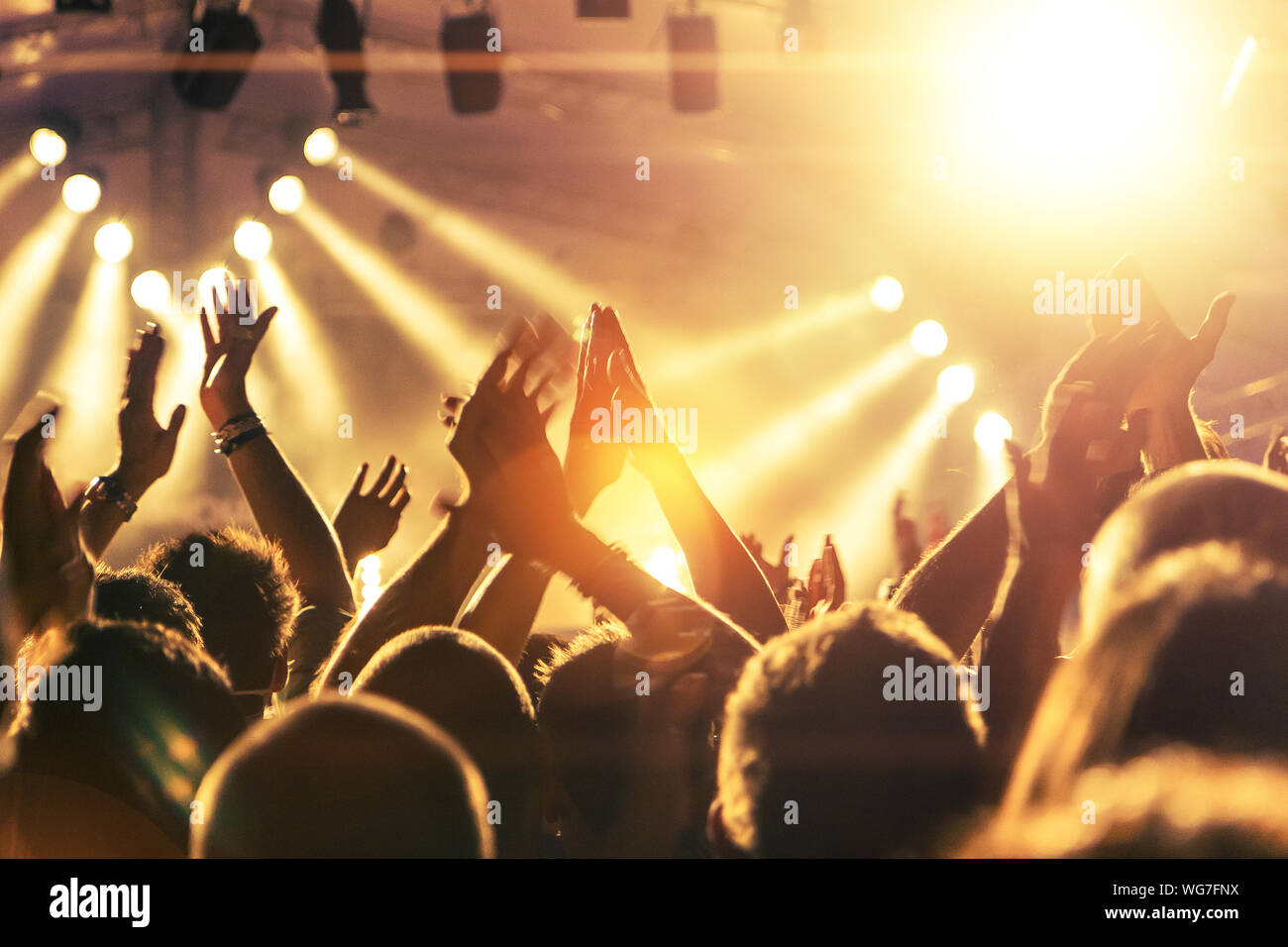 Concert crowd clapping in front of a bright stage Stock Photo - Alamy